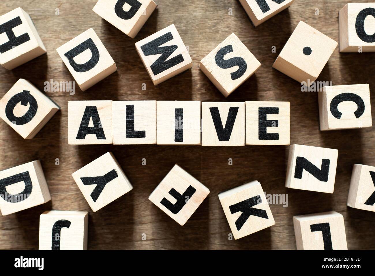 Wood letter block in word alive on wood background with another ...