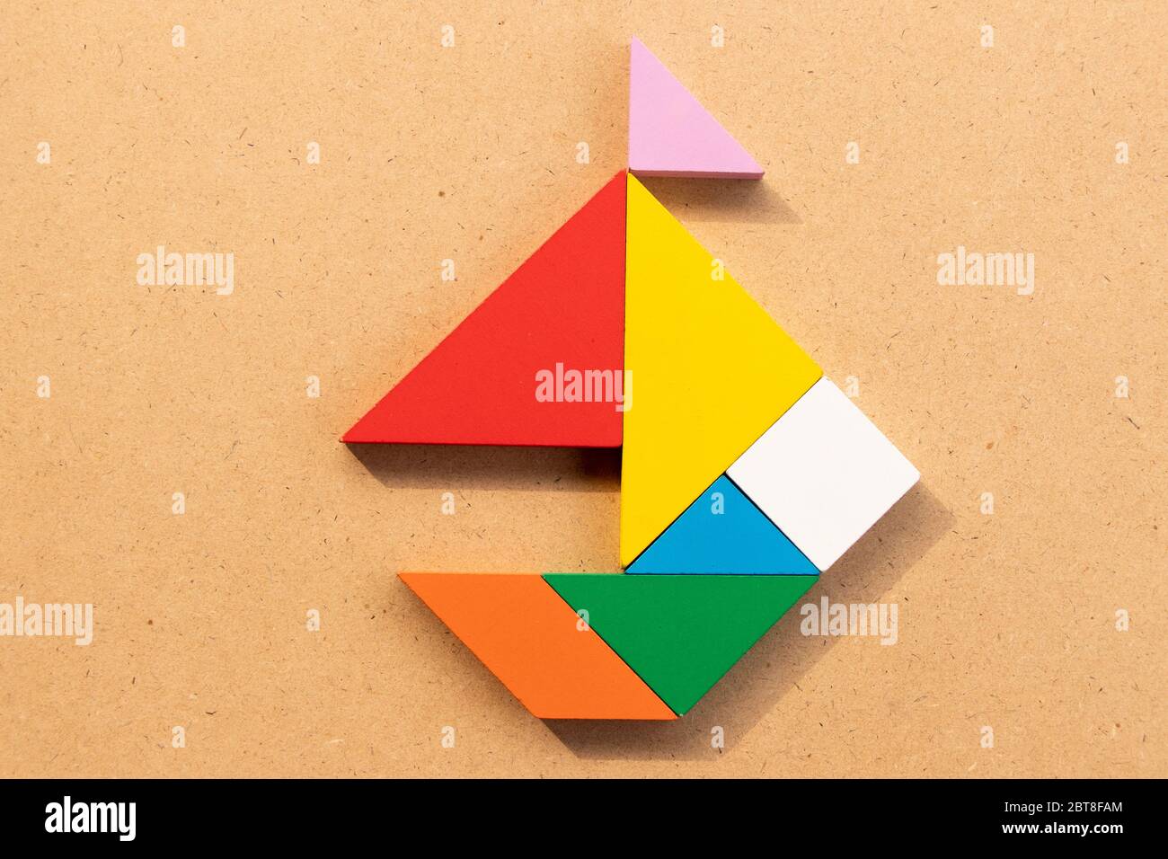 Color tangram puzzle in sailing ship or yacht shape on wood bacground ...