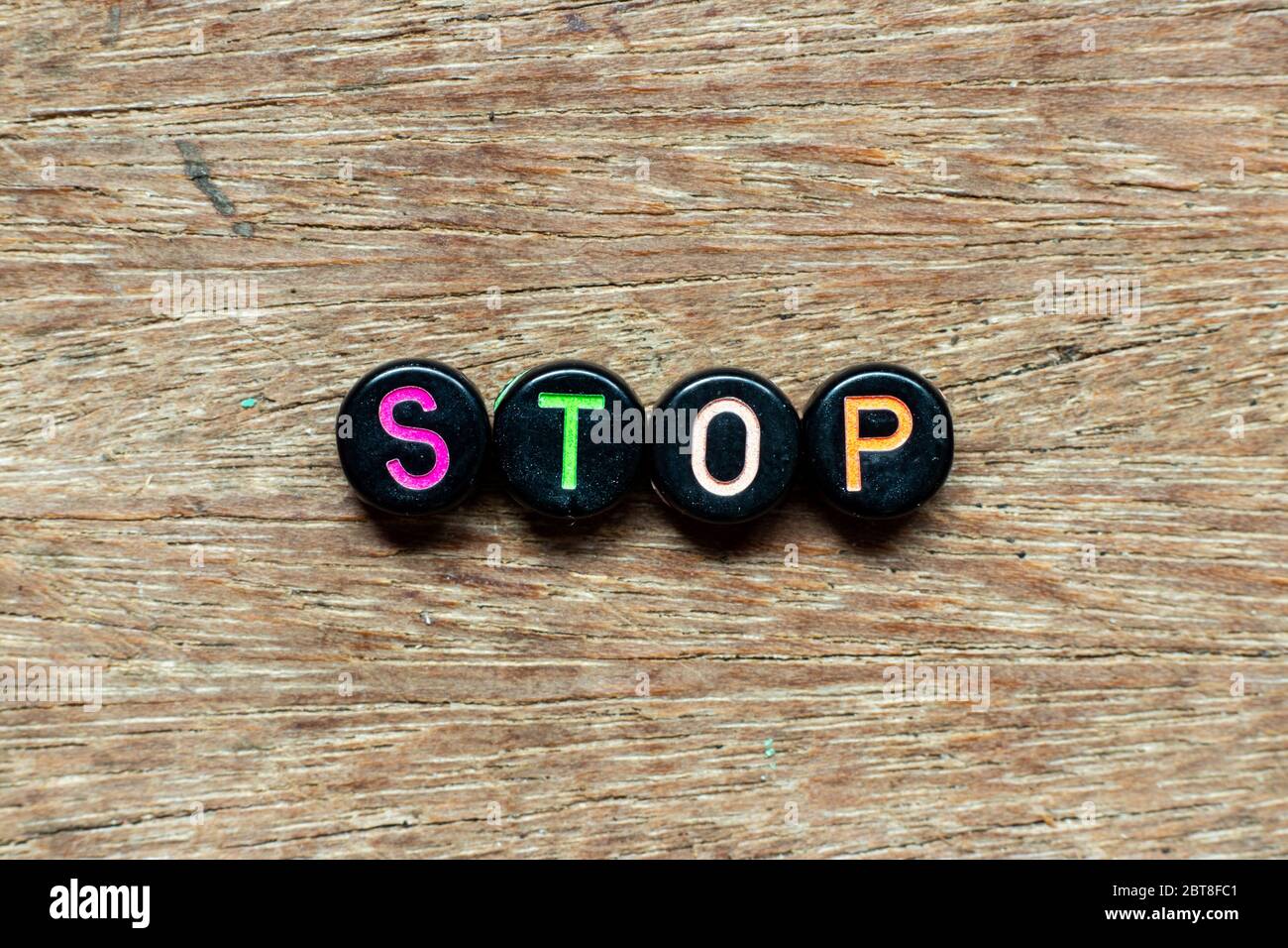 Black bead with color letter in word stop on wood background Stock ...
