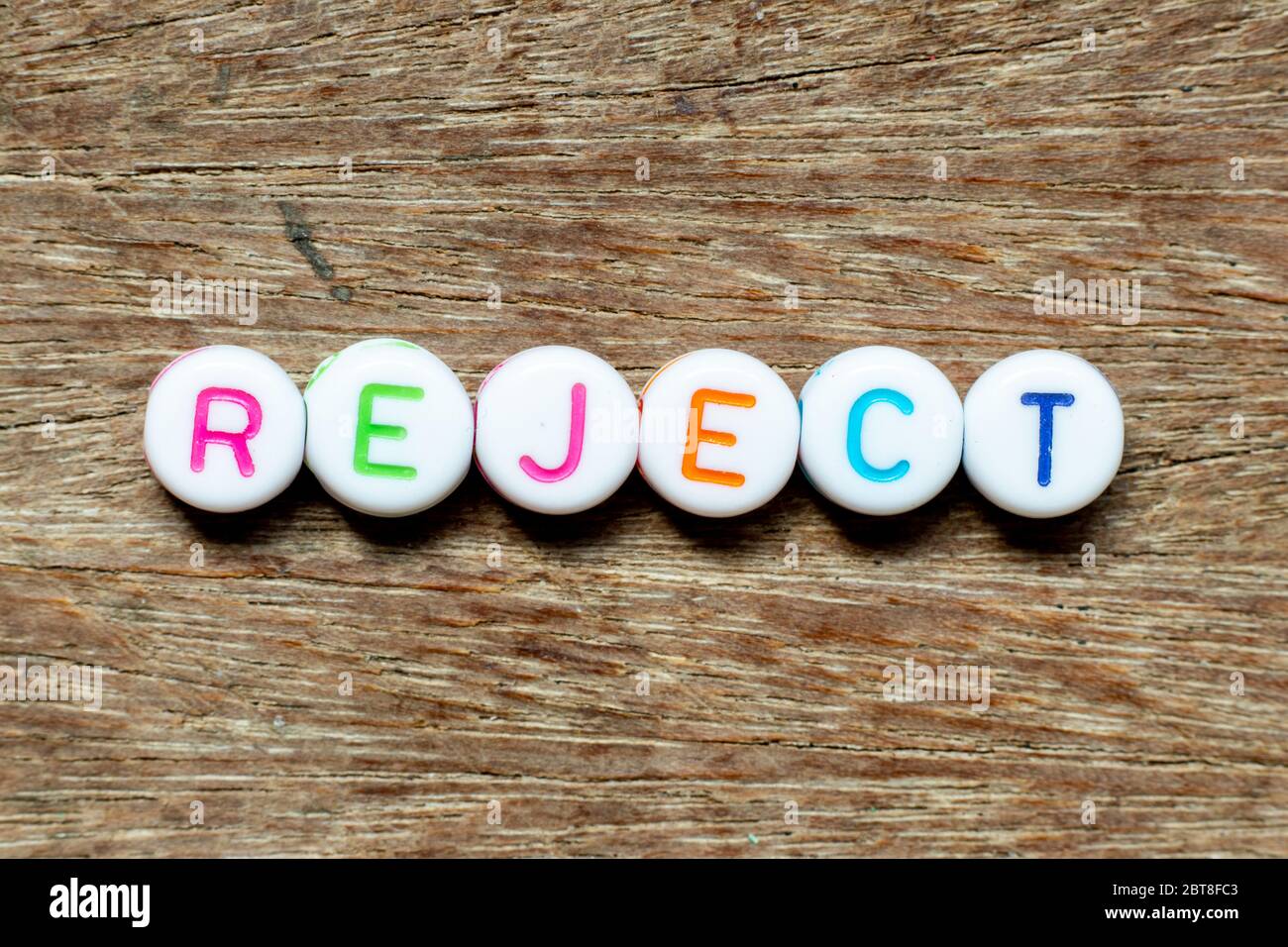 White bead with color letter in word reject on wood background Stock ...