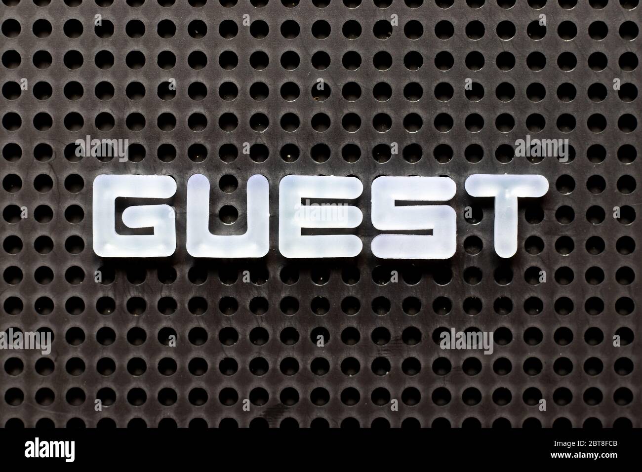 White color alphabet with word guest on black pegboard background Stock ...