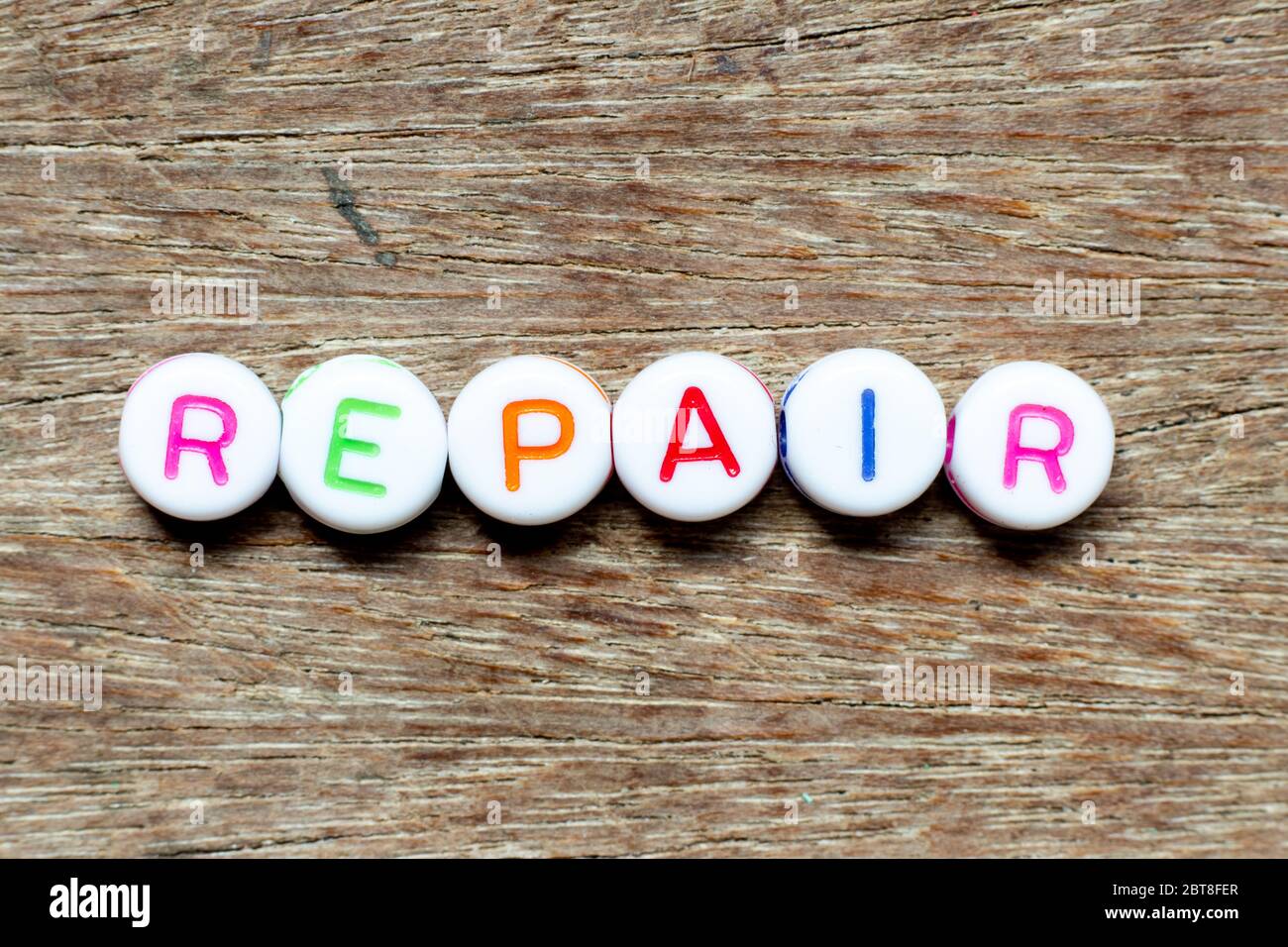 White bead with color letter in word repair on wood background Stock ...