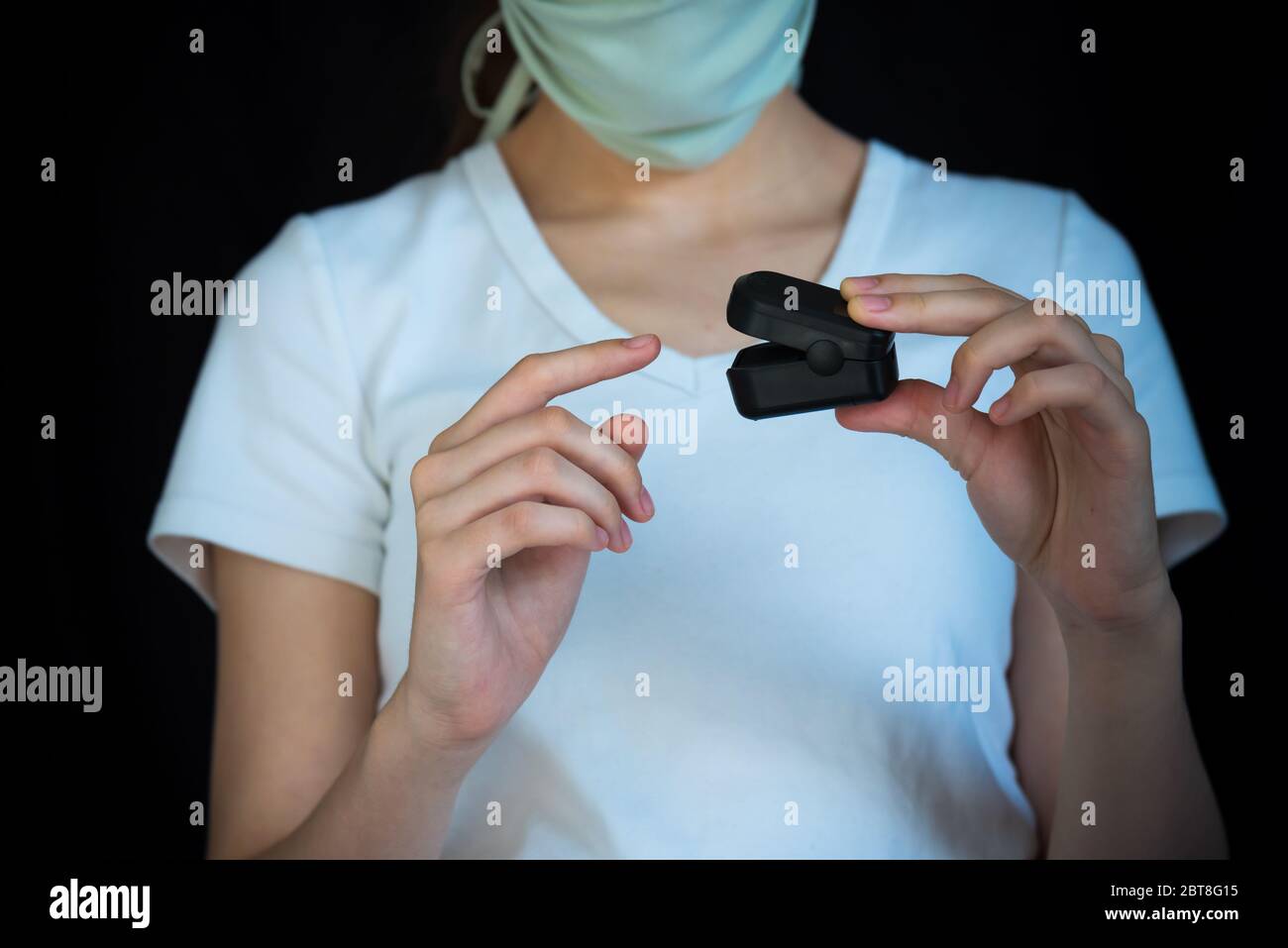 Close-up of woman wearing face mask and putting pulse oximeter on ...