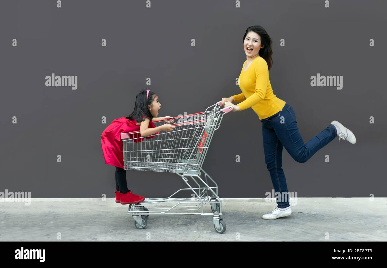happy mom and kid go shopping cart together. Funny action of mother and ...