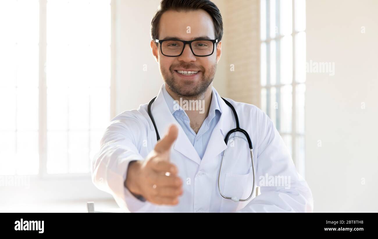 Smiling male doctor stretch hand greeting with patient Stock Photo - Alamy