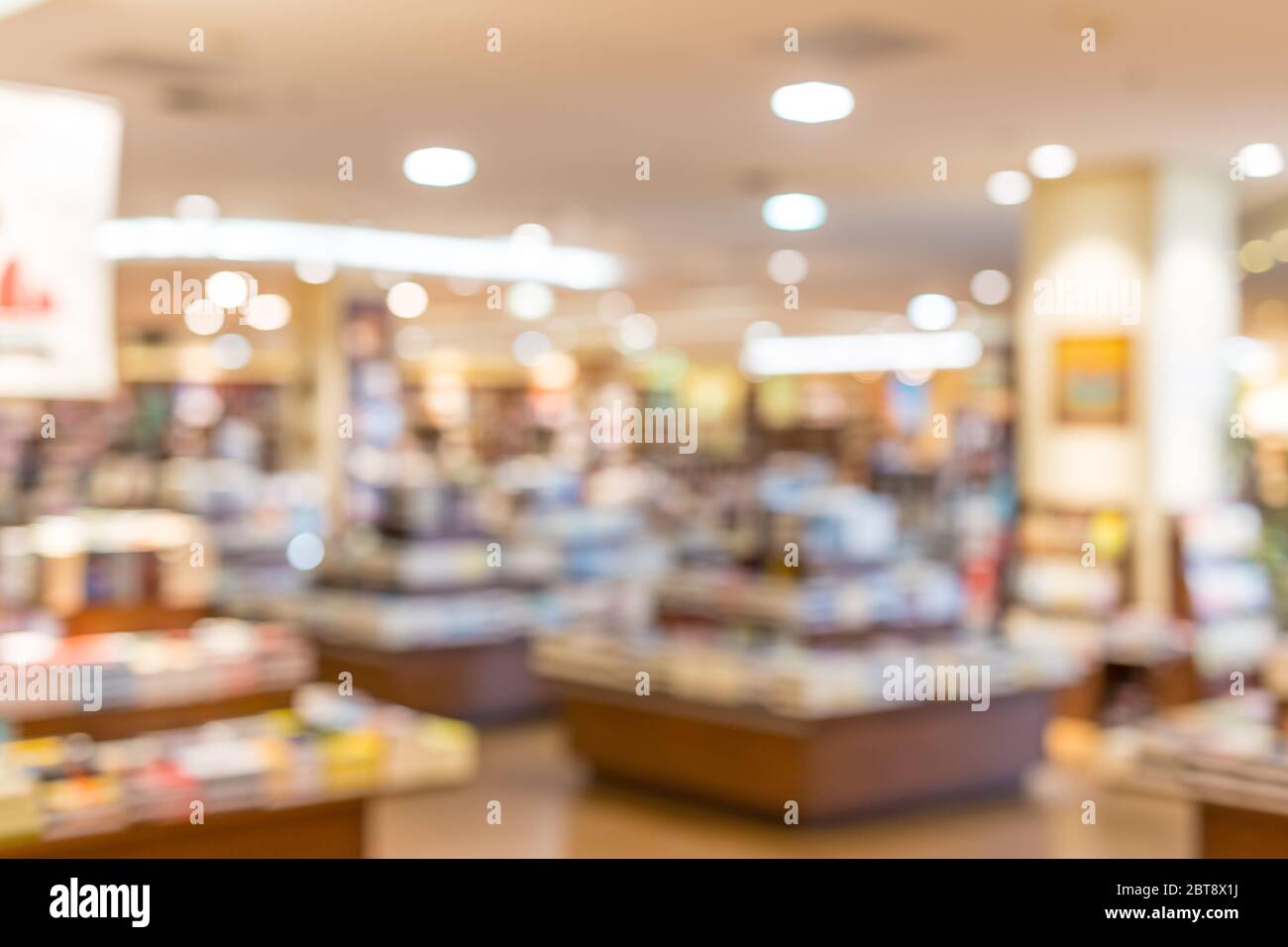 De focused blur image of a bookstore with lights and book stand ...