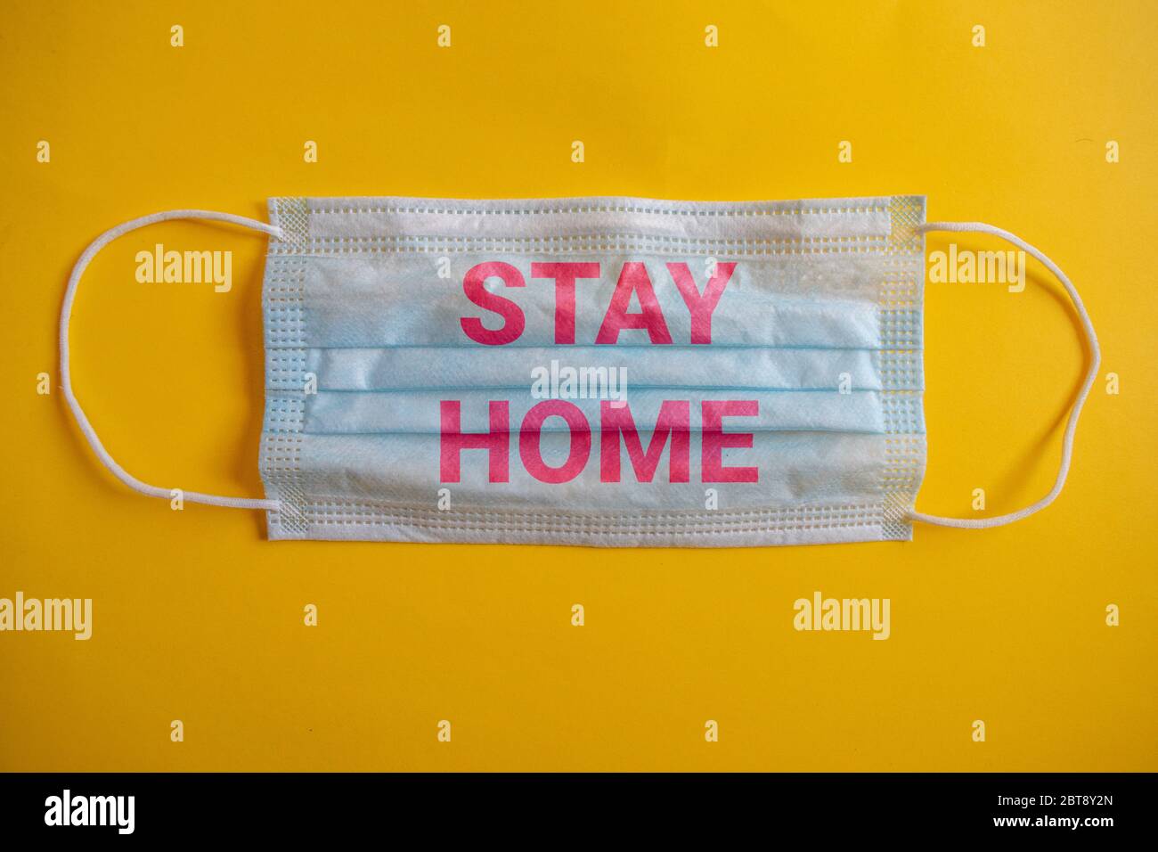 medical mask with the phrase stay home. with yellow isolated background ...