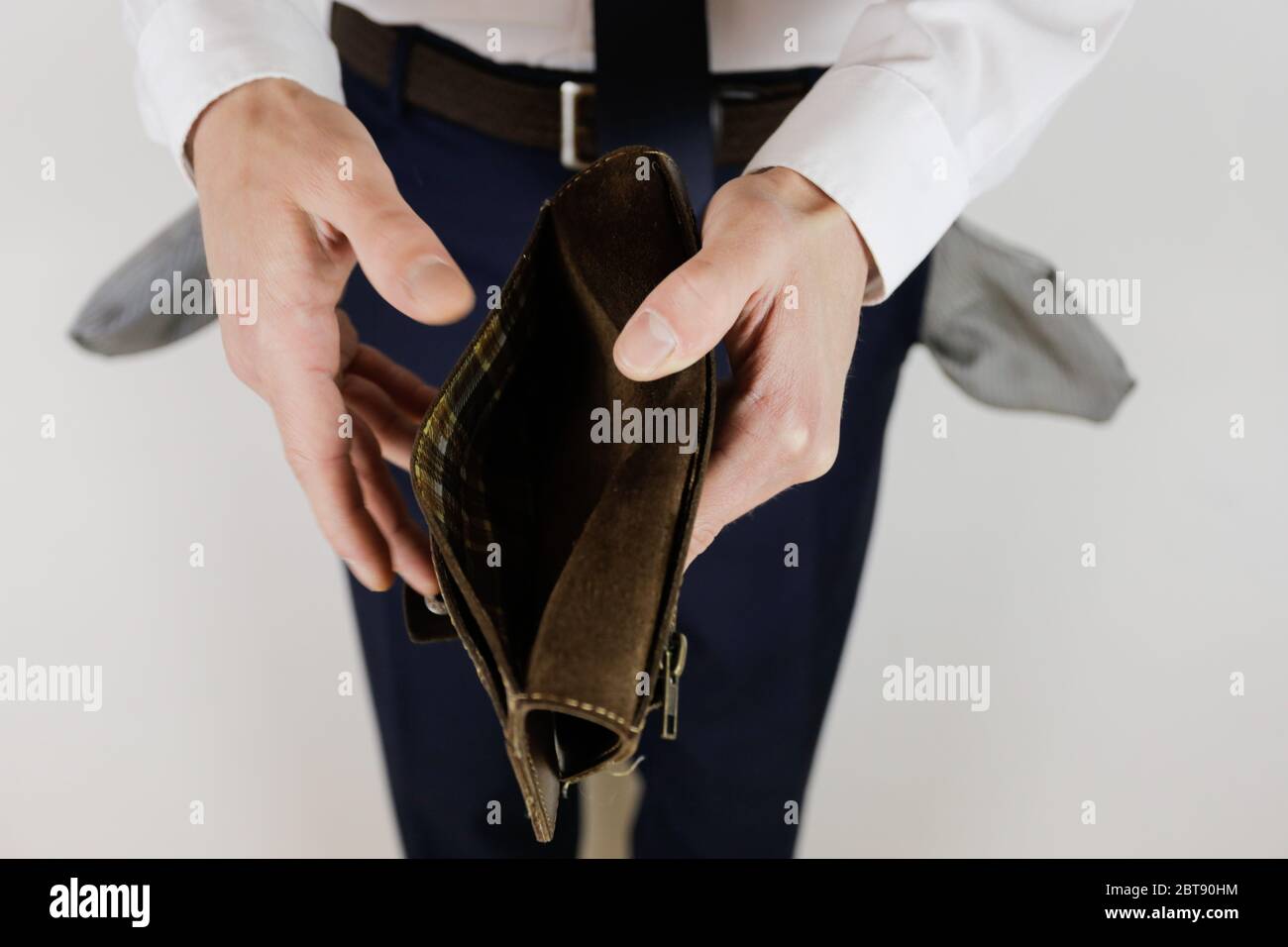 A man in a business suit holds in his hands an empty wallet without ...