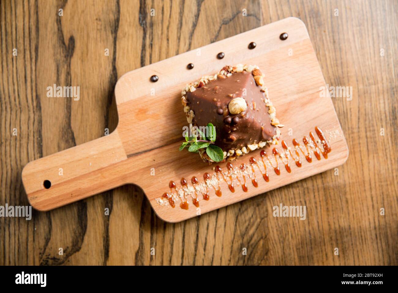 Chocolate pyramid shape cake with nuts on the wooden plate Stock Photo ...