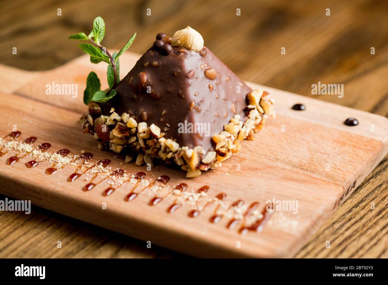 Chocolate pyramid shape cake with nuts on the wooden plate Stock Photo ...