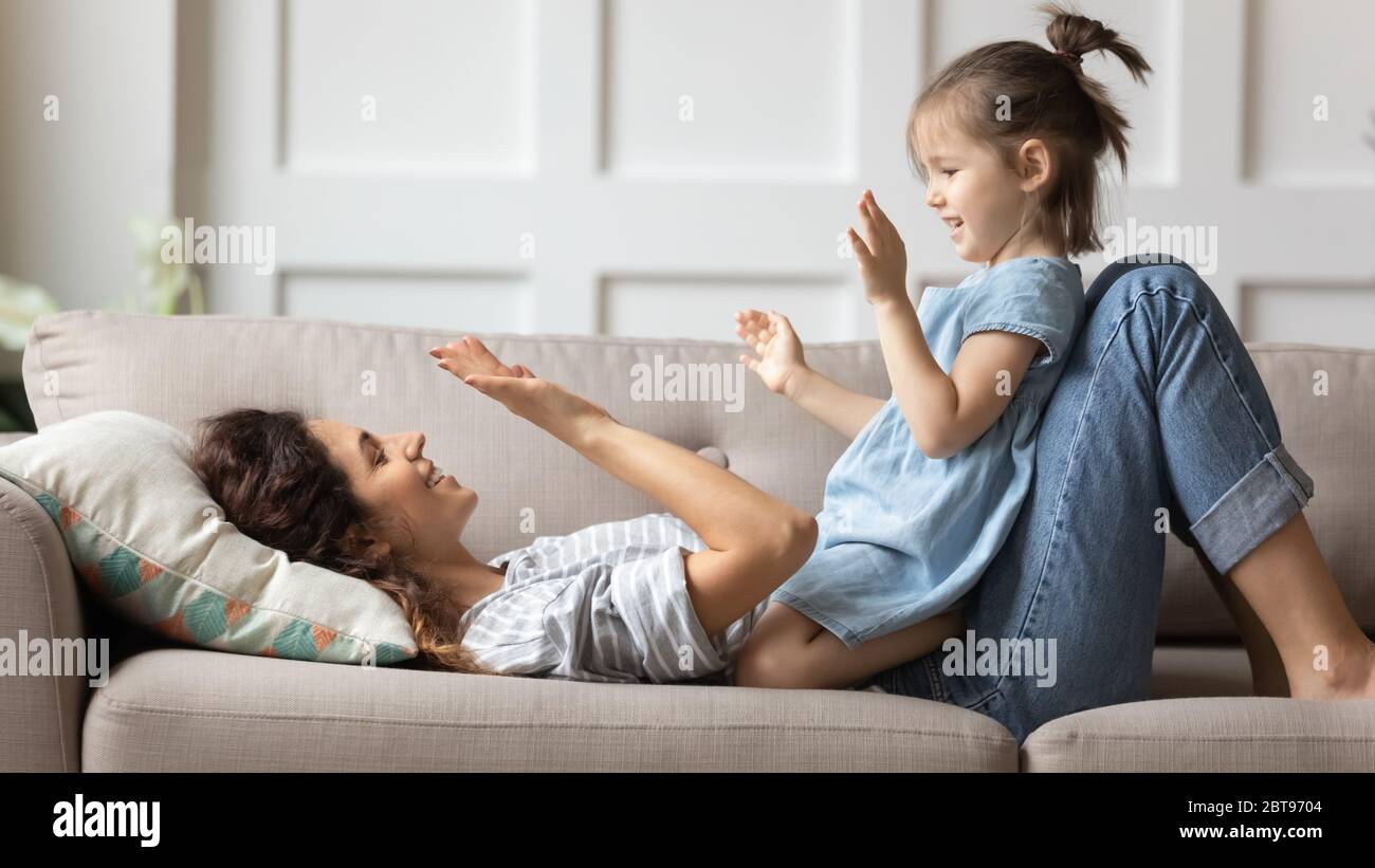 Smiling mother playing with little daughter, clapping hands on couch Stock Photo - Alamy