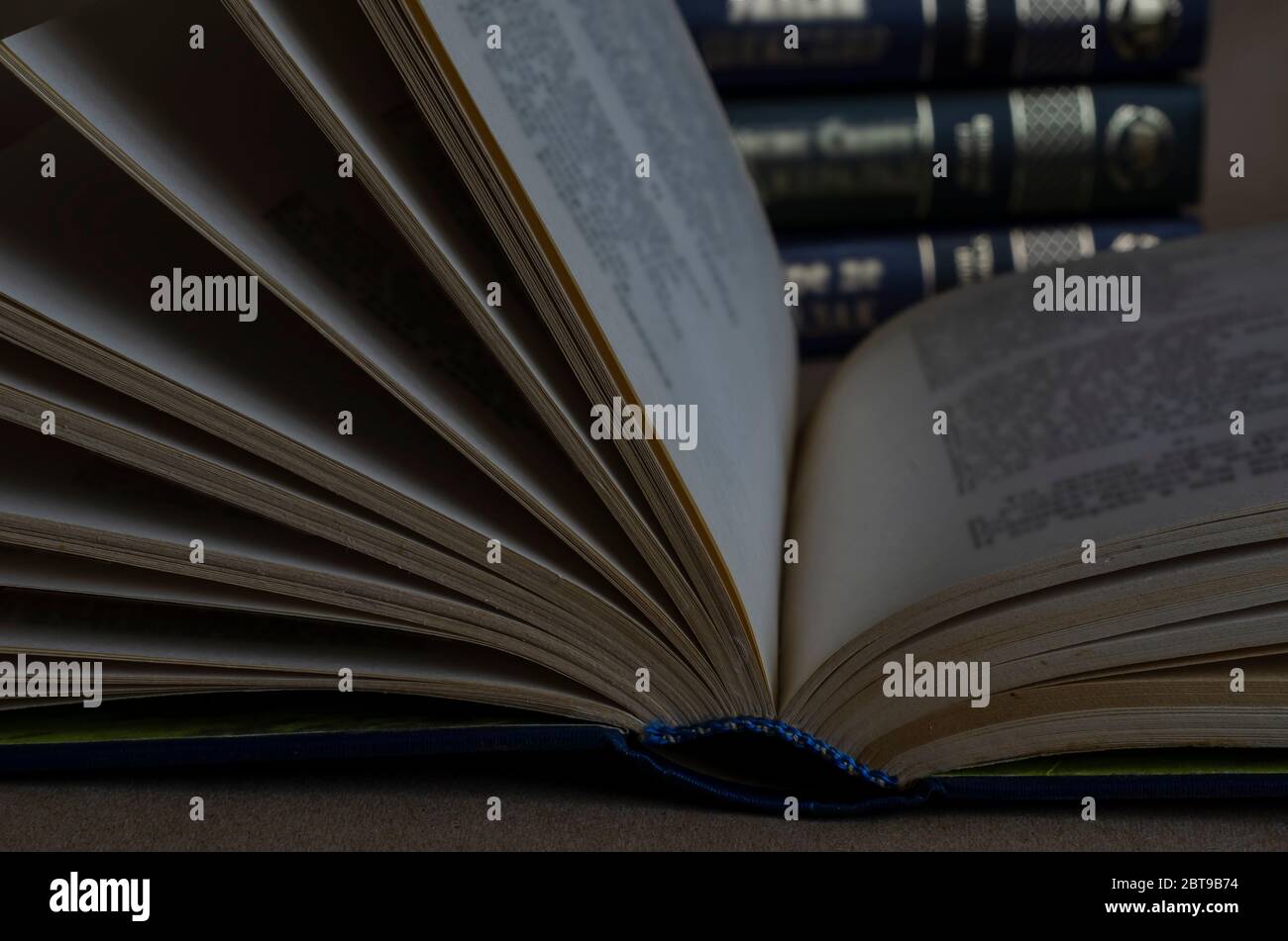 An open book on a table in a dark library. Close-up of a hardback book ...