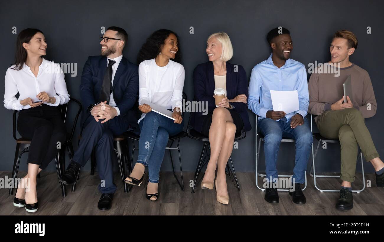 Happy diverse business people sitting in row, waiting for interview ...