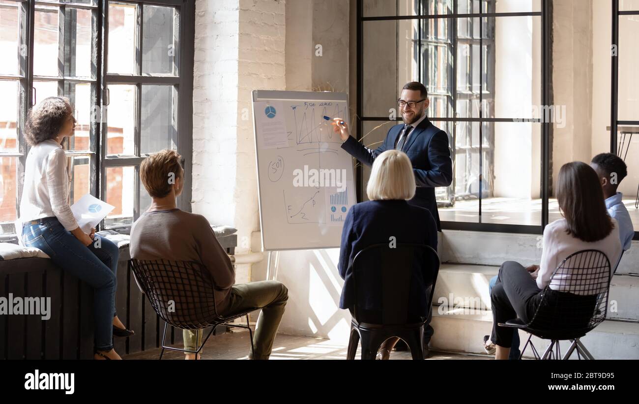 Smiling businessman coach giving flip chart presentation at briefing ... Smiling businessman coach giving flip chart presentation at briefing ...