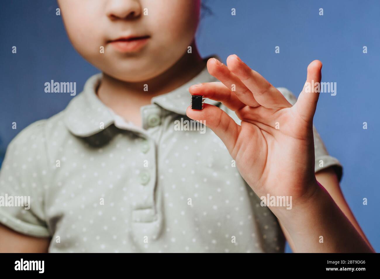 A girl holds in her hand and examines a small black chip. Chipization ...