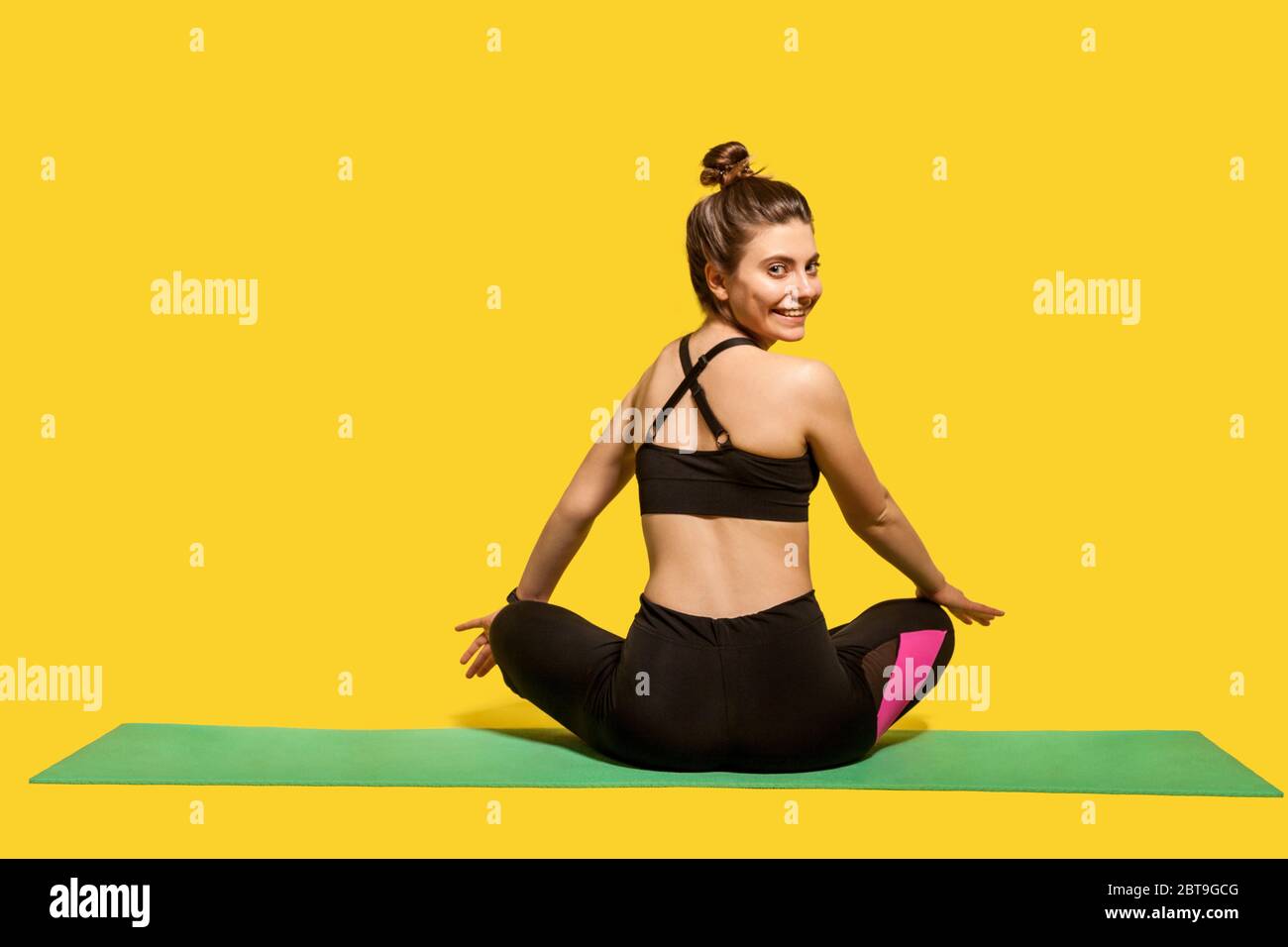 Back View Cheerful Woman With Hair Bun In Tight Sportswear Sitting In