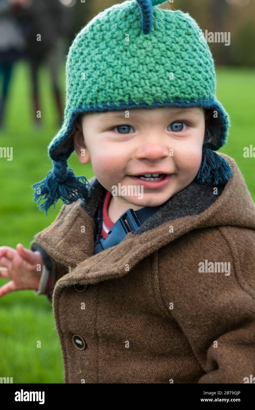 Adorable one year old little boy grinning cheekily and excited to be ...