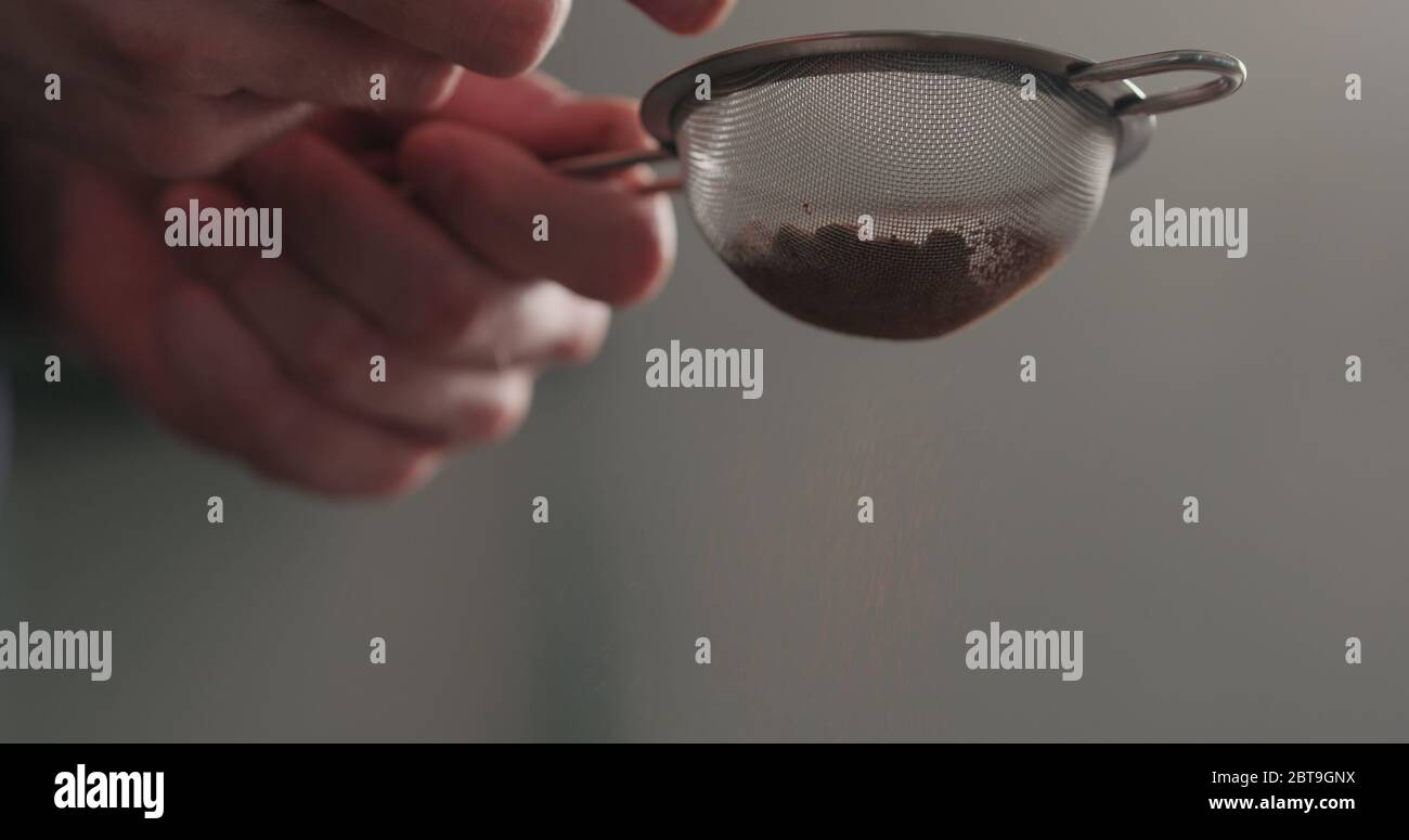 man hand sprinkle cocoa powder from sieve Stock Photo - Alamy