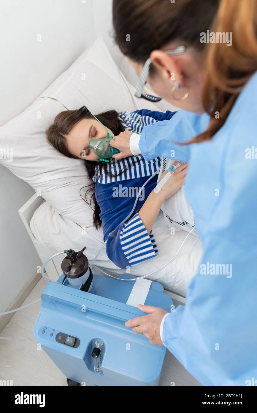 The teenager has a breathing ventilator connected. The doctor adjusts ...