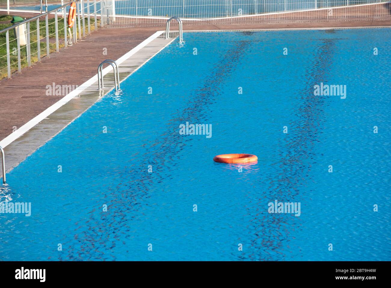 Orange lifebuoy floating on the surface of blue water in a pool Stock ...