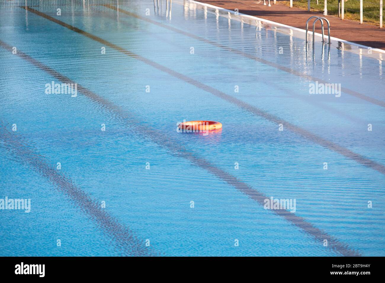Orange lifebuoy floating on the surface of blue water in a pool Stock ...