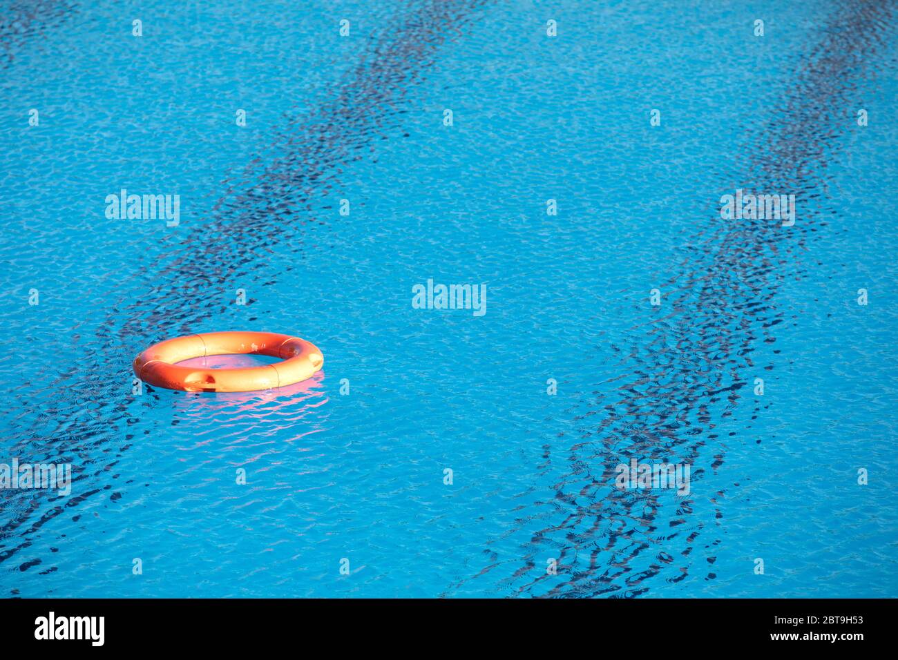 Orange lifebuoy floating on the surface of blue water in a pool Stock ...