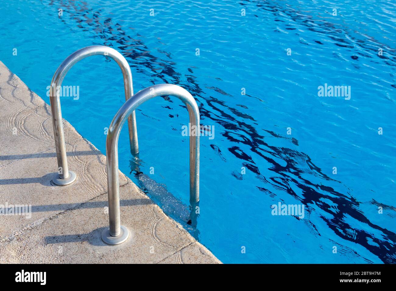 Steel railings stairs in a pool with a blue water Stock Photo - Alamy