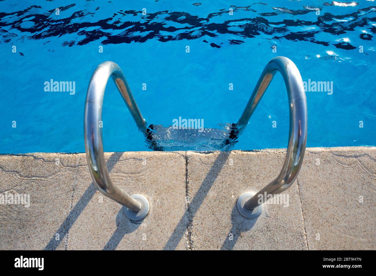 Steel railings stairs in a pool with a blue water Stock Photo - Alamy