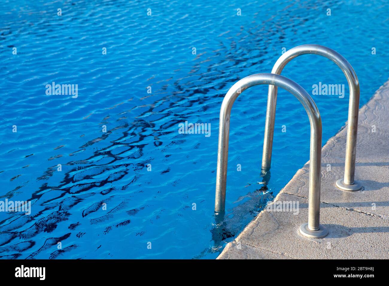 Steel railings stairs in a pool with a blue water Stock Photo - Alamy