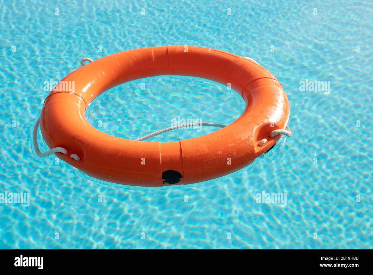 Orange lifebuoy floating on the surface of blue water in a pool Stock ...