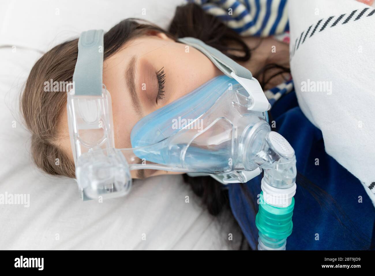 Oxygen mask attached to the respiratory tract. The teenager lies in a ...