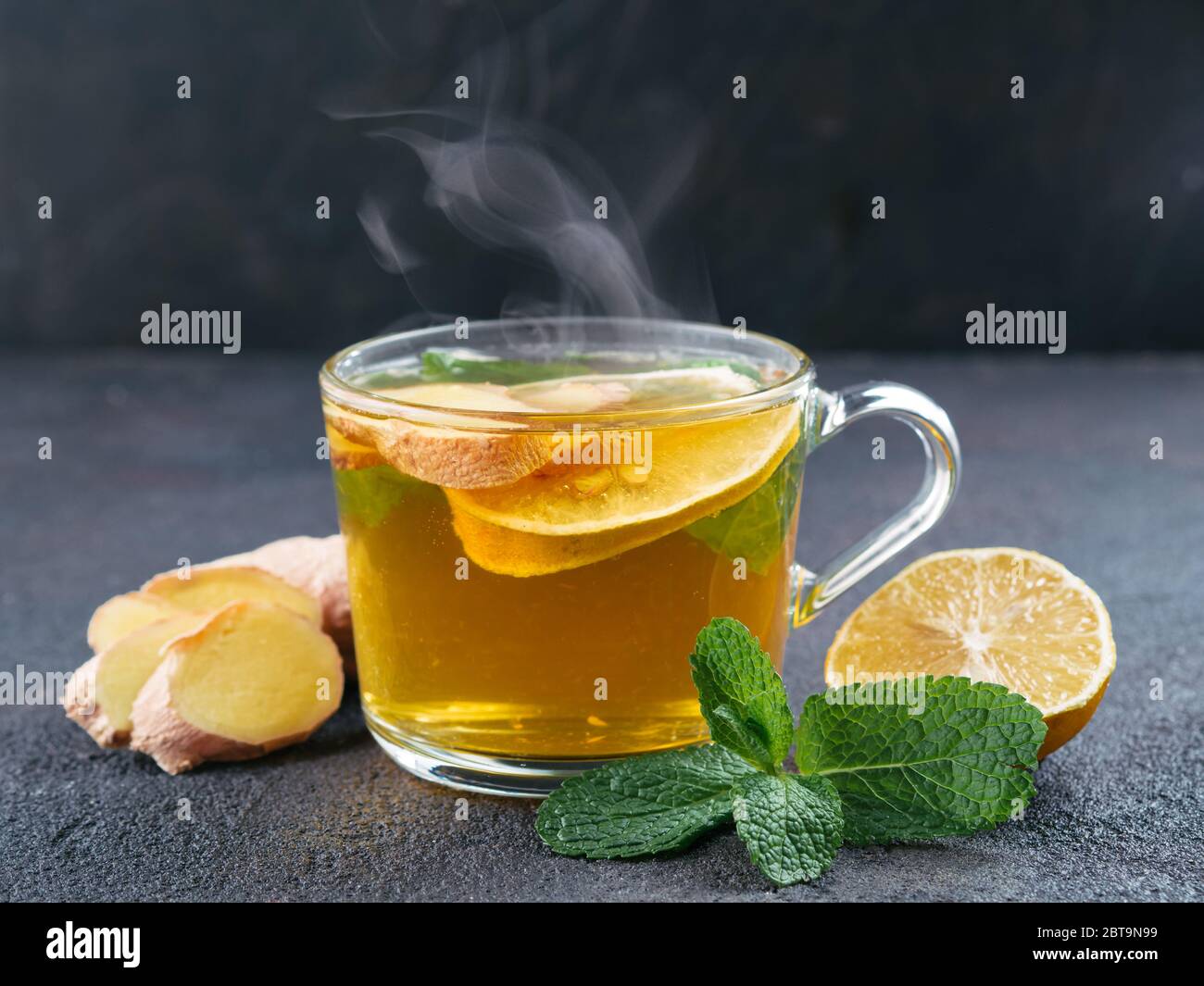 Herbal tea with ginger, mint and lemon. Hot tea glass cup with steam ...