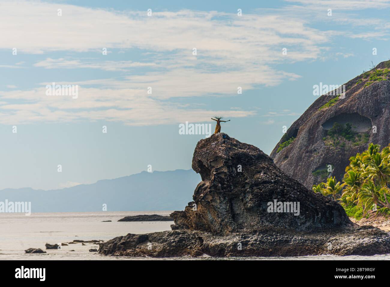 Fijian island inhabitant dancing on a rock in the sea, close to an ...