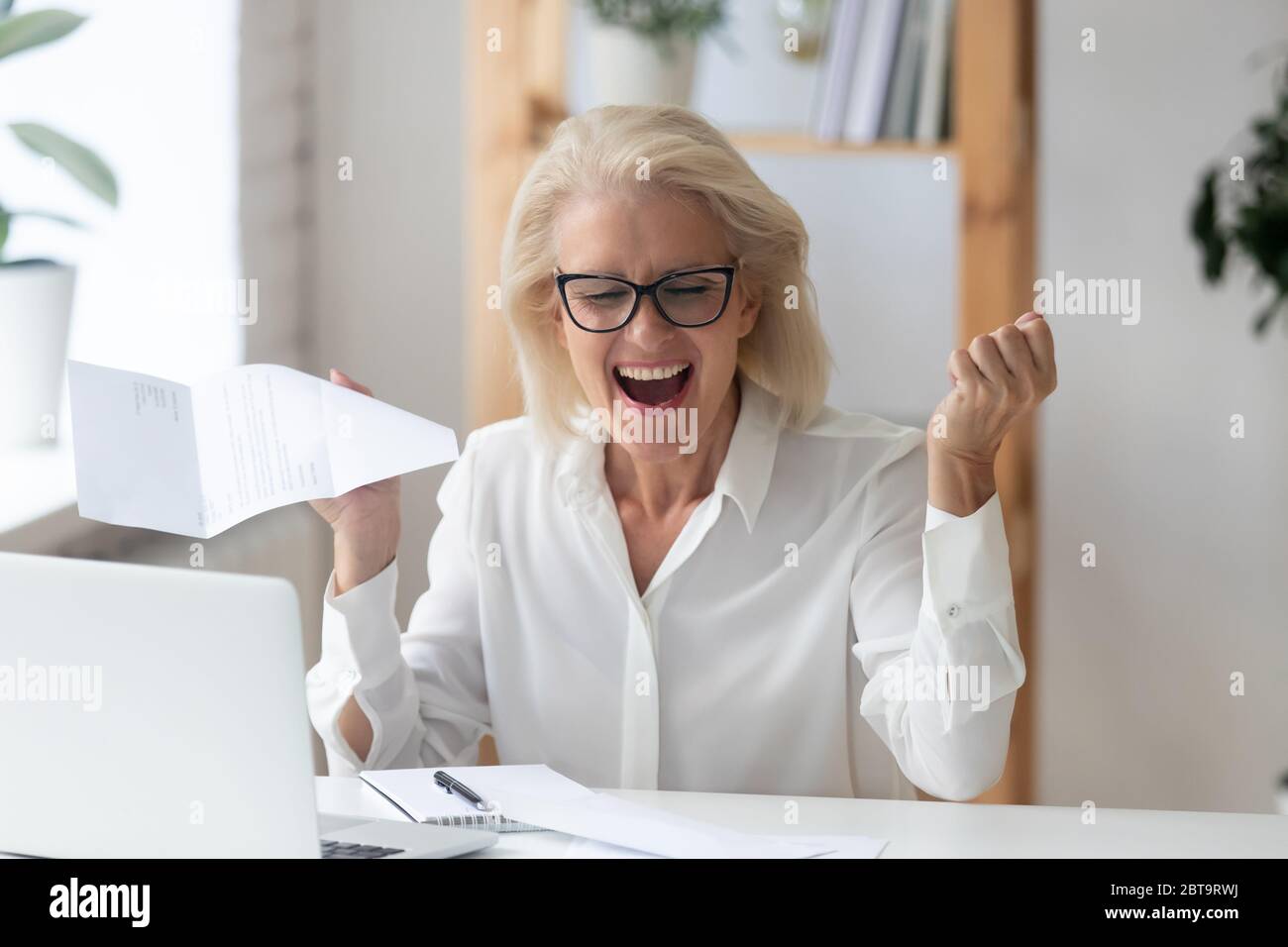 Overjoyed senior female employee excited with letter correspondence ...