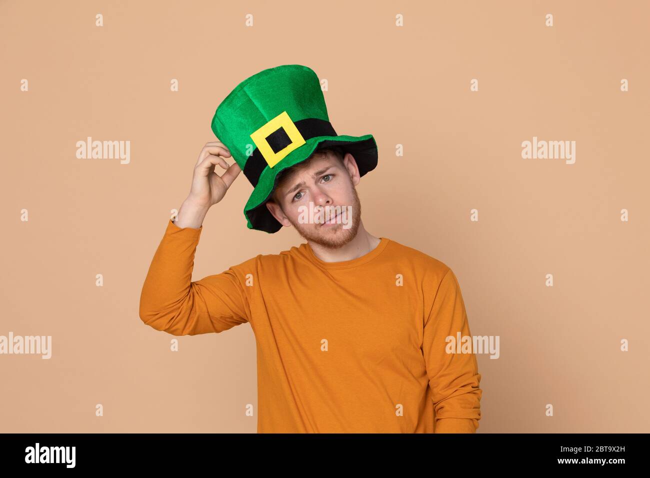 Attractive young guy with a big green hat on a yellow background Stock ...