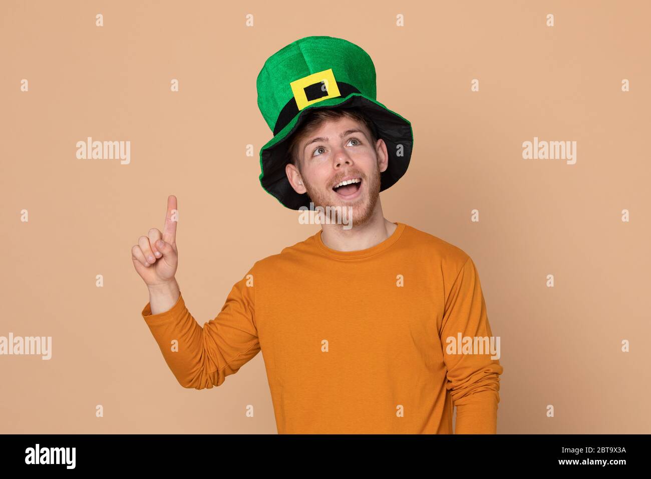 Attractive young guy with a big green hat on a yellow background Stock ...