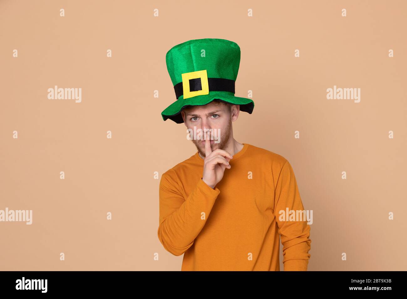 Attractive young guy with a big green hat on a yellow background Stock ...
