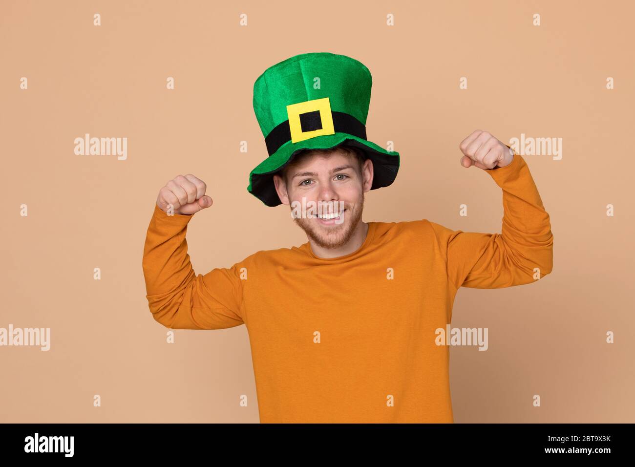 Attractive young guy with a big green hat on a yellow background Stock ...