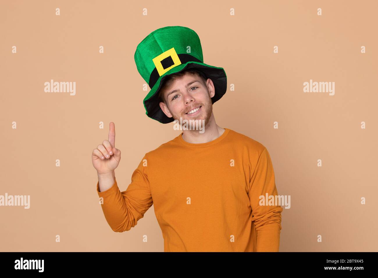 Attractive young guy with a big green hat on a yellow background Stock ...