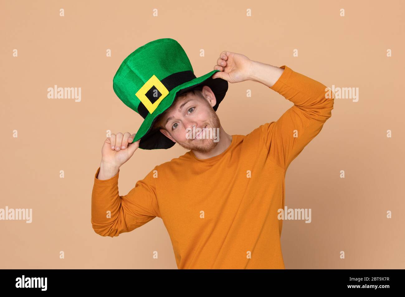 Attractive young guy with a big green hat on a yellow background Stock ...