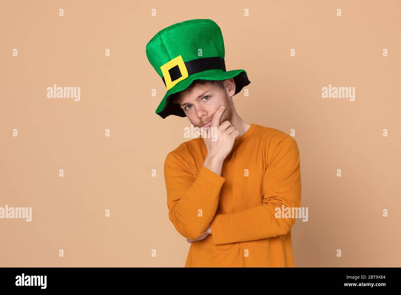Attractive young guy with a big green hat on a yellow background Stock ...