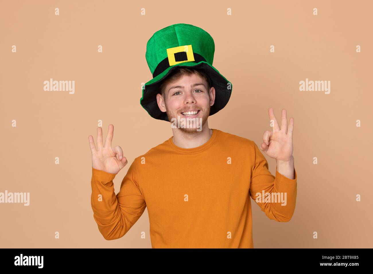 Attractive young guy with a big green hat on a yellow background Stock ...