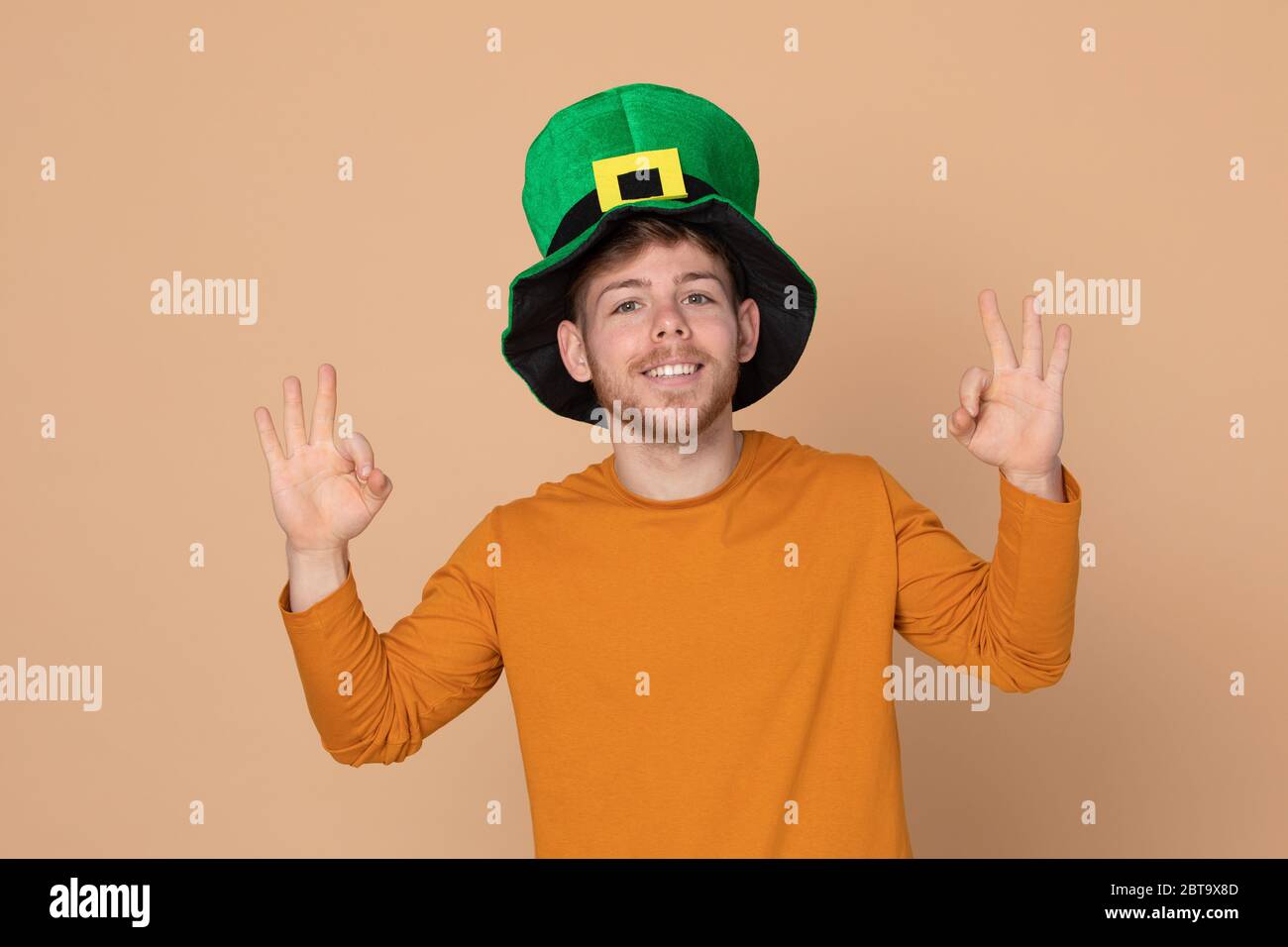 Attractive young guy with a big green hat on a yellow background Stock ...