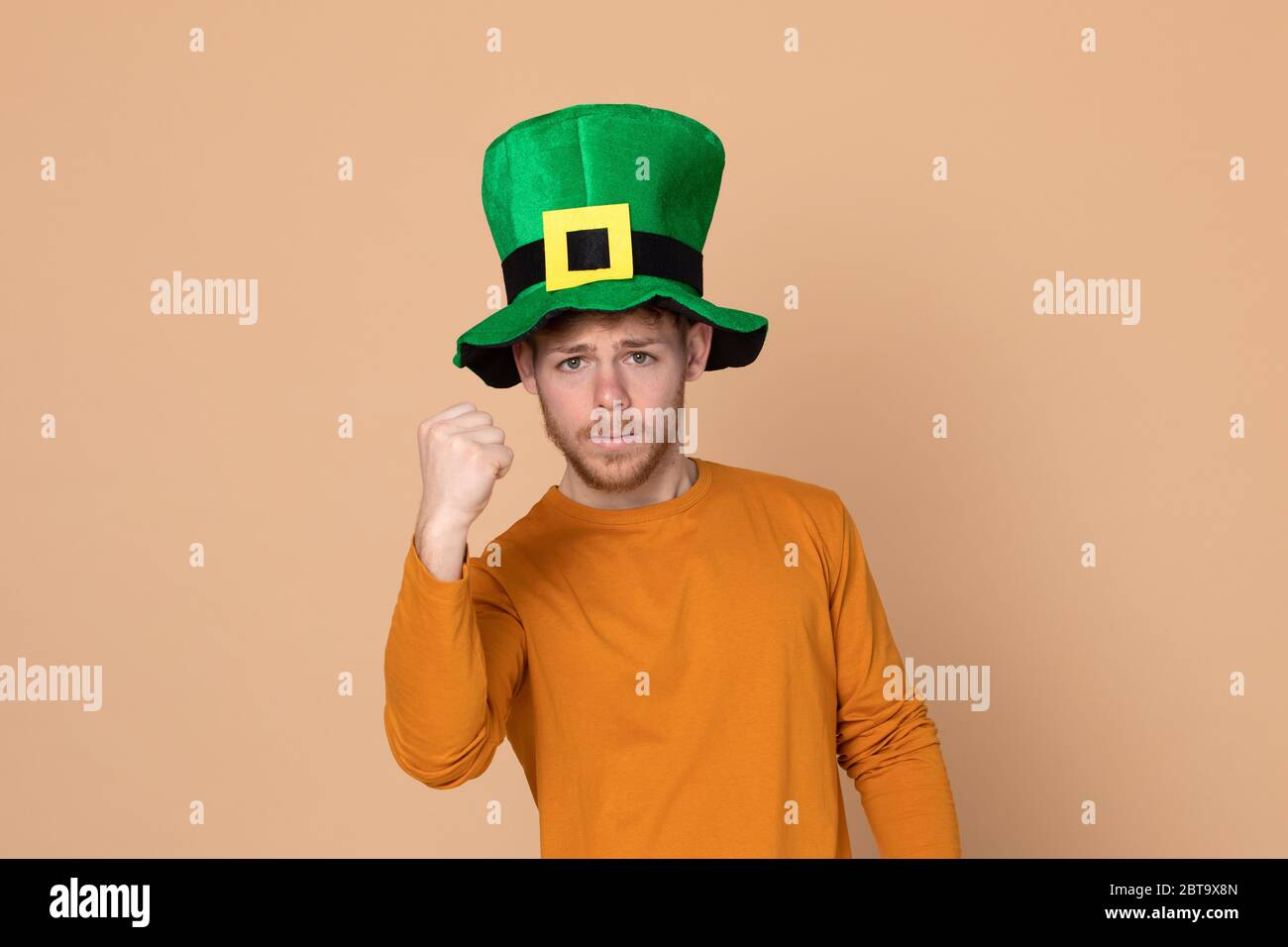 Attractive young guy with a big green hat on a yellow background Stock ...