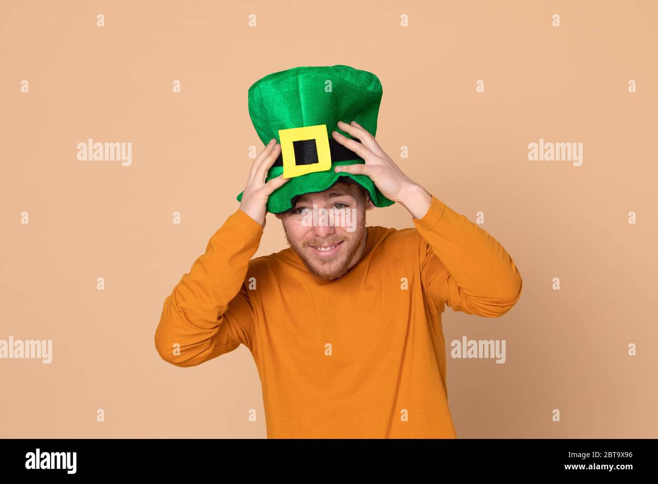 Attractive young guy with a big green hat on a yellow background Stock ...
