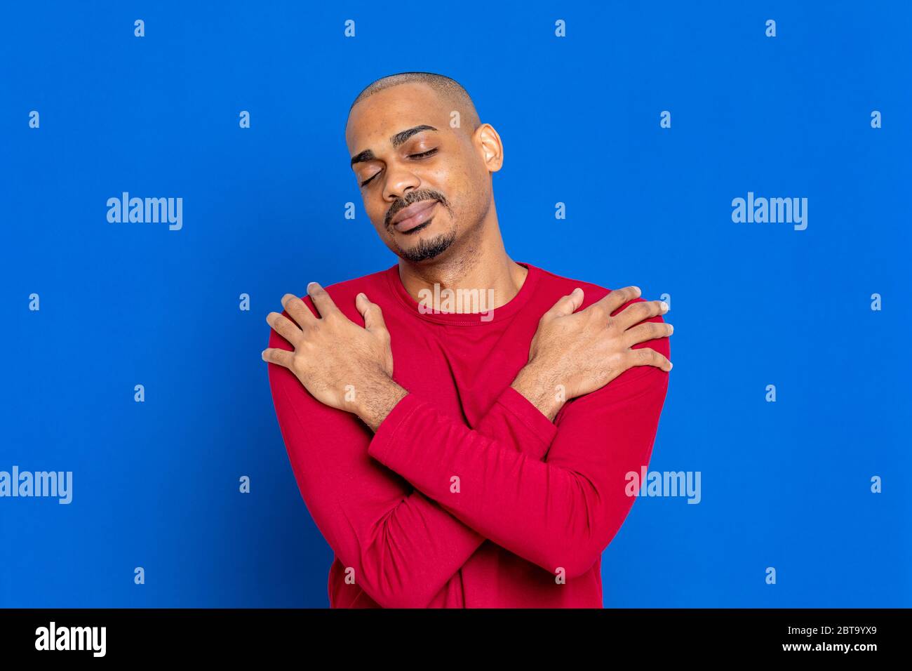 African man with red T-shirt on a blue background Stock Photo - Alamy