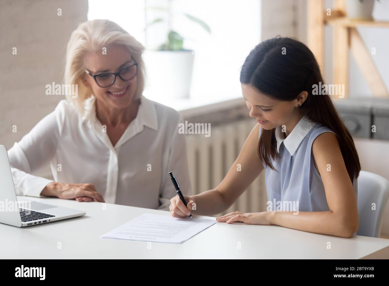 Young applicant sign contract with middle-aged businesswoman Stock ...