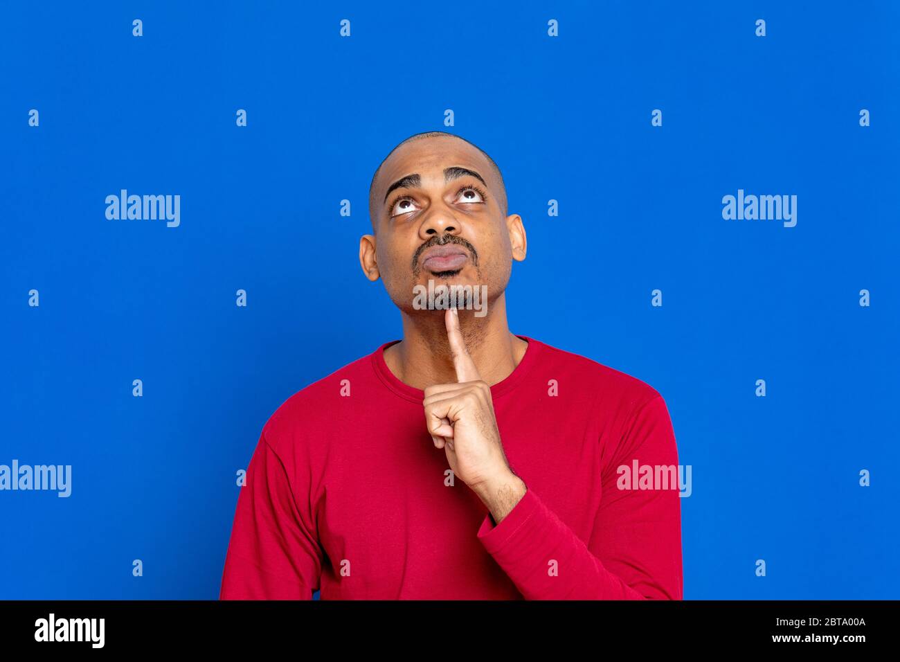 African guy on a blue background thinking Stock Photo - Alamy