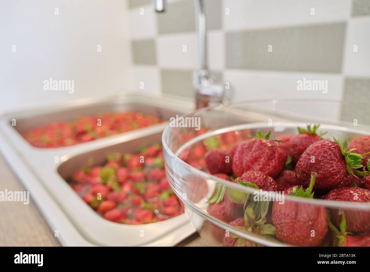 Strawberry season, washing berries in water in wash basin at home ...