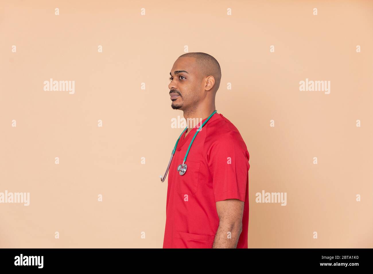 African doctor wearing a red uniform on a orange background Stock Photo ...